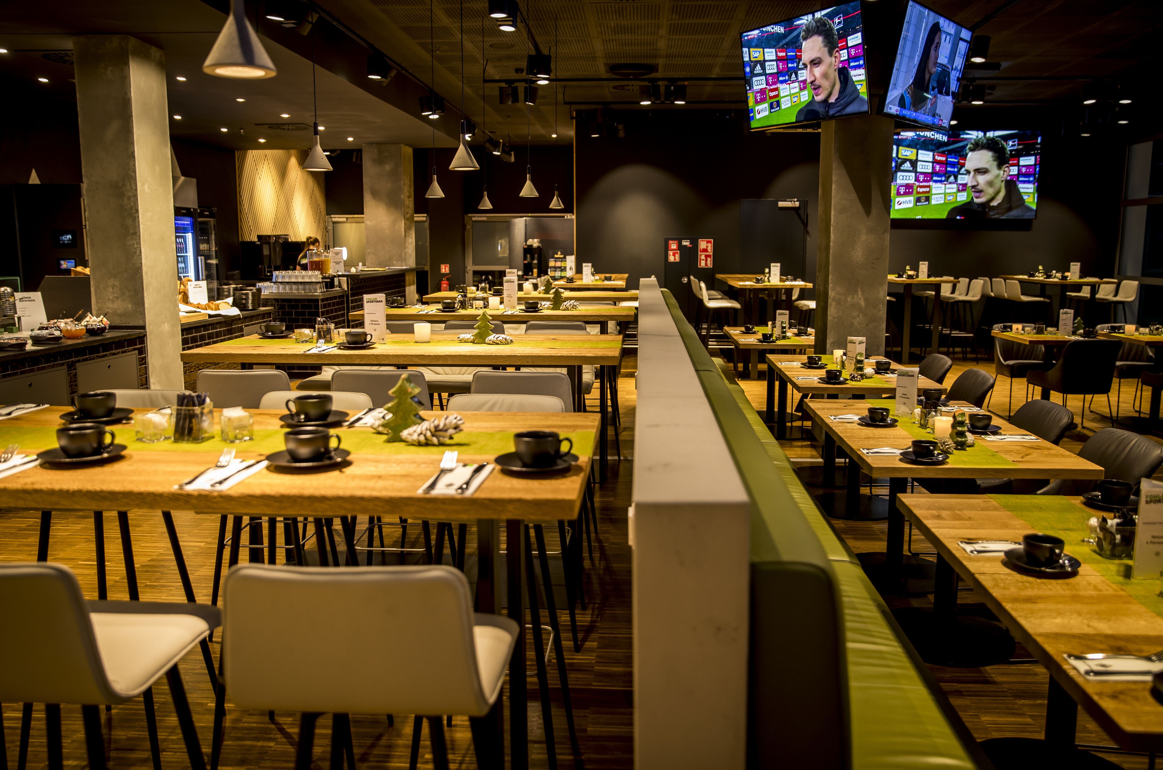 Um restaurante moderno com várias mesas e cabines, equipado com televisores de tela plana exibindo eventos esportivos.