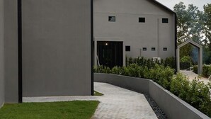 Um edifício moderno com um caminho pavimentado que leva a uma entrada com portão.