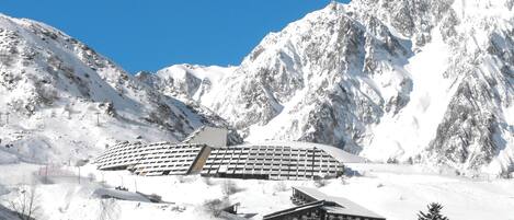 Uma montanha coberta de neve com um edifício grande, com telhado inclinado e várias janelas.