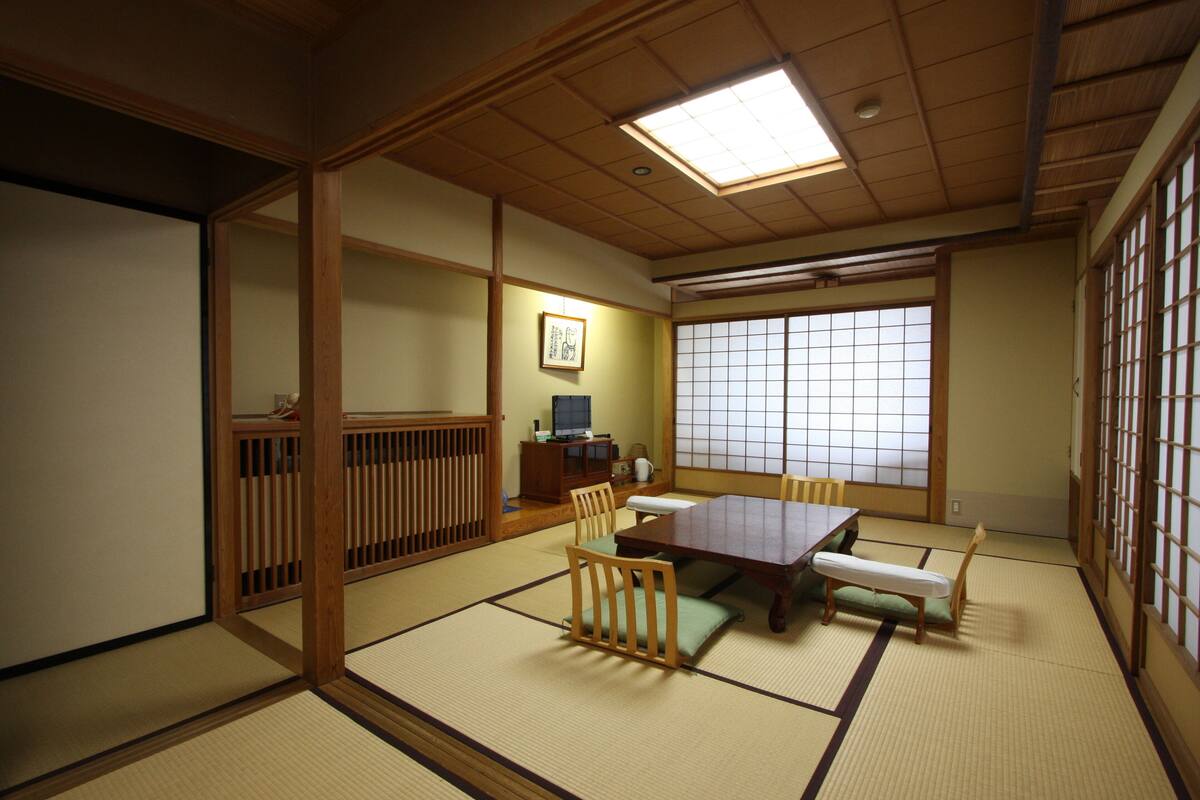 Um quarto japonês tradicional com piso de tatame, uma mesa baixa e mobiliário de madeira.