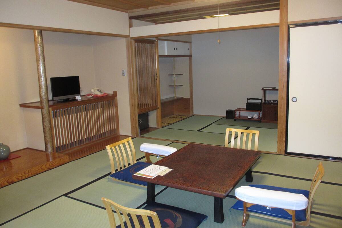 Um quarto japonês tradicional com tatames, uma mesa baixa e cadeiras de madeira.