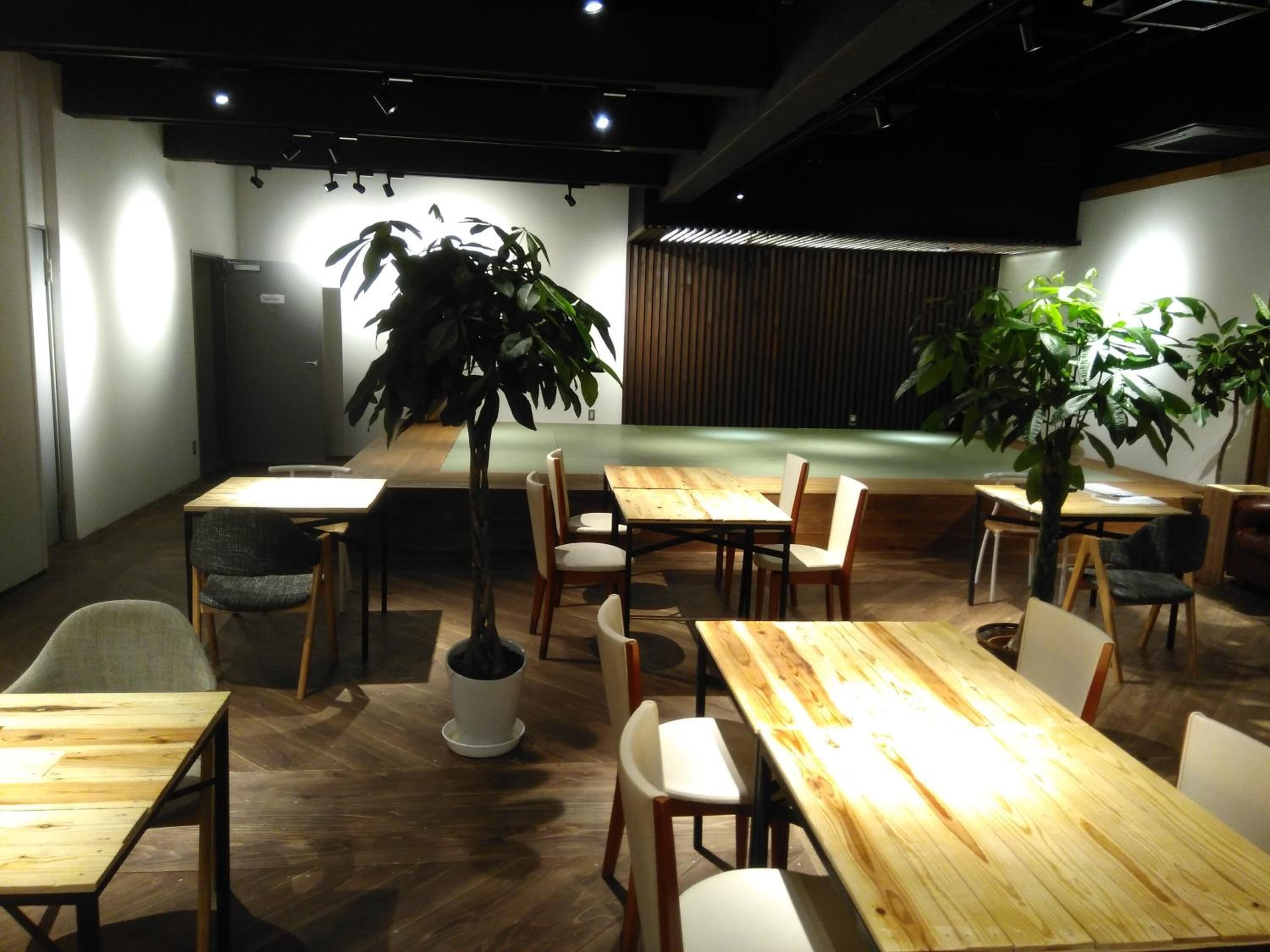 Uma sala de conferências com mesas e cadeiras de madeira, um palco e plantas em vasos.