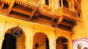 Um edifício tradicional com varandas ornamentadas e uma placa indicando ser uma pensão e restaurante.