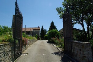 Rua estreita com um portão e muros de pedra em ambos os lados.