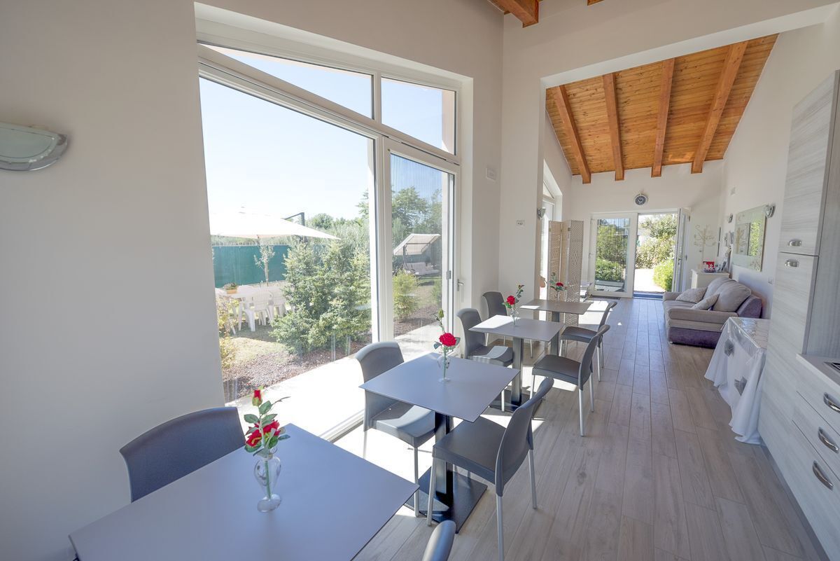 Uma sala de jantar luminosa com grandes janelas, teto de madeira e vista para o exterior.
