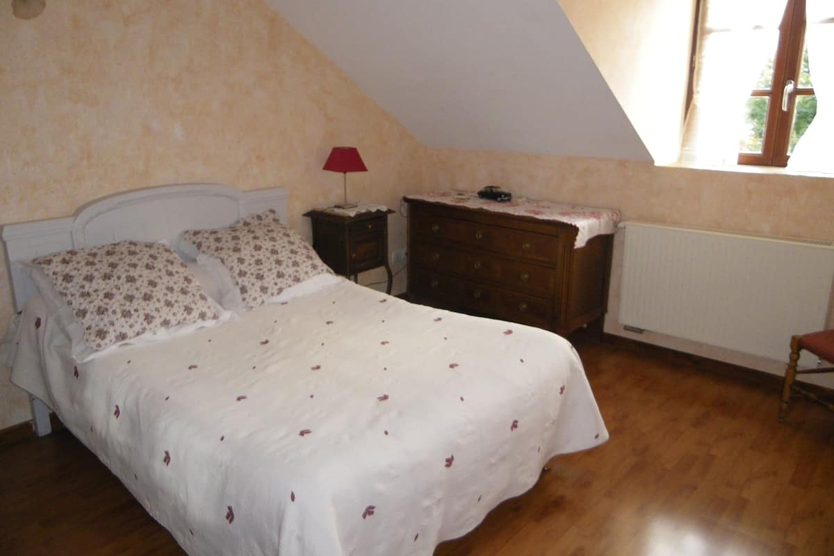 Quarto com cama, penteadeira, mesa de cabeceira e janela com vista.
