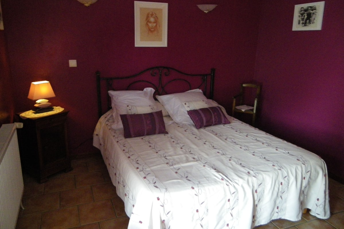 Quarto com duas camas, mesa de cabeceira com abajur e uma cadeira.