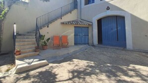 Um edifício com escadaria, uma porta azul e duas cadeiras laranja.