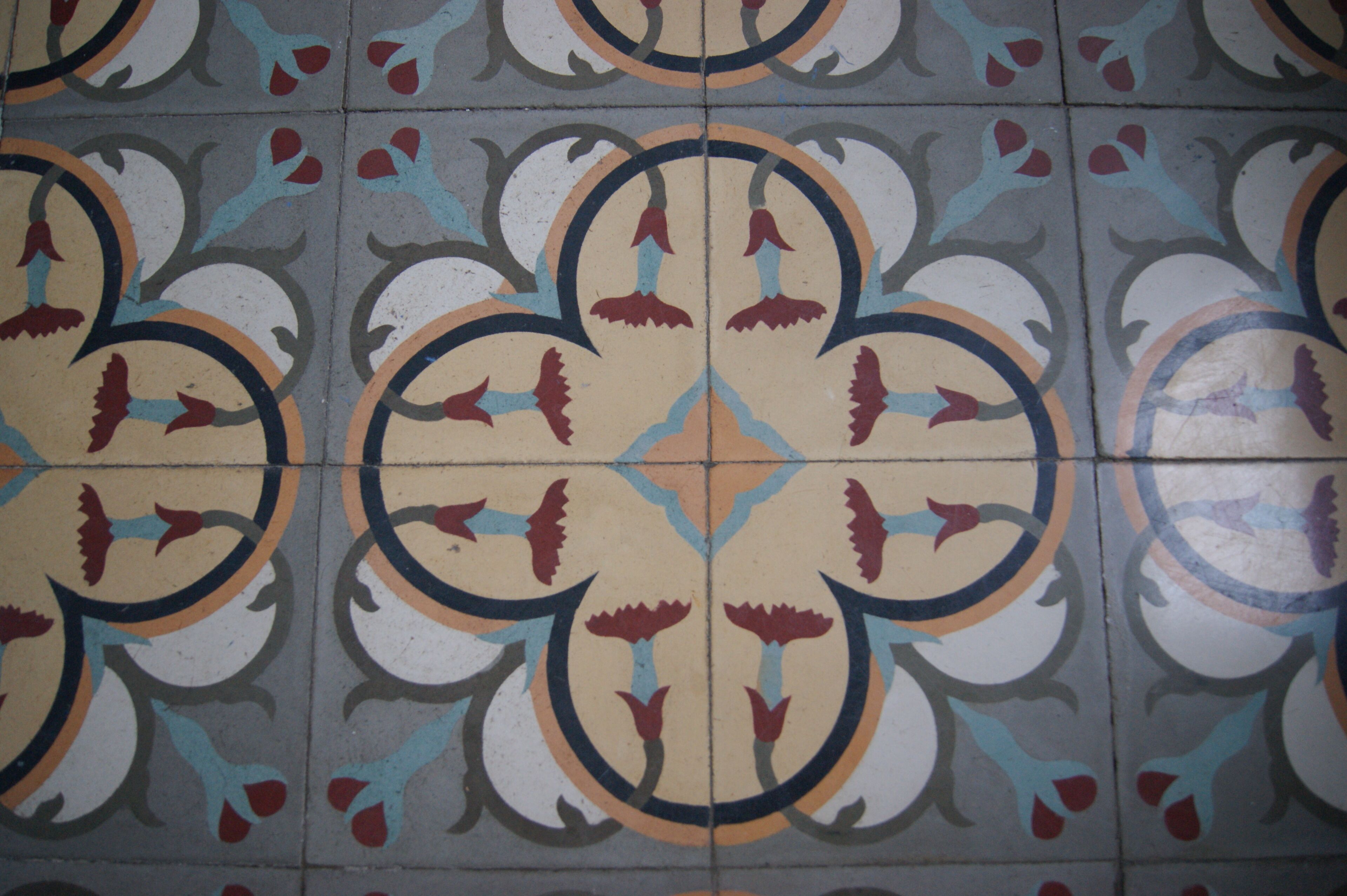 Piso de azulejos com um padrão floral simétrico.