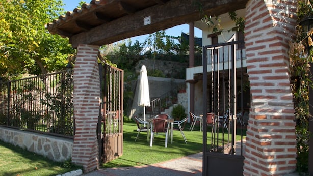 Área de pátio com mobiliário externo, pérgola e parede de tijolos.