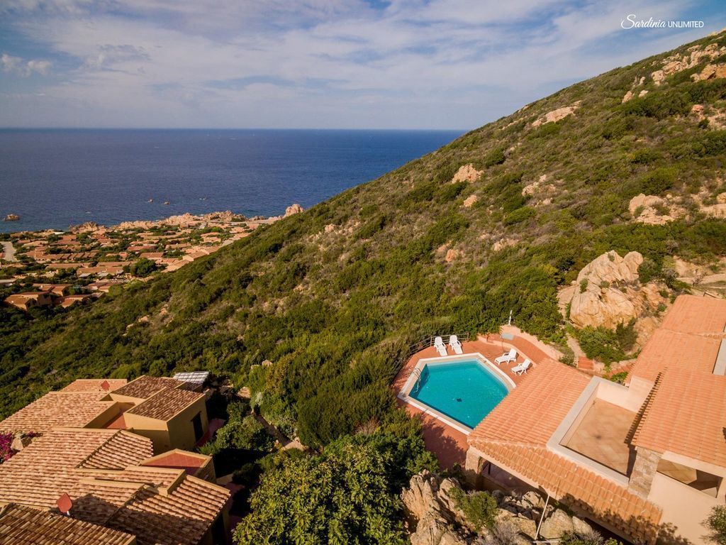 Uma villa numa encosta com piscina, telhados de terracota e vista para o mar.