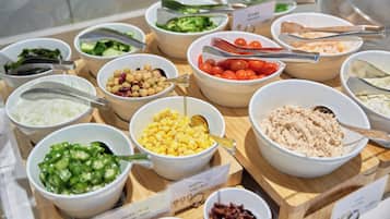 Buffet com diversos pratos, incluindo saladas, legumes e outras opções de comida.