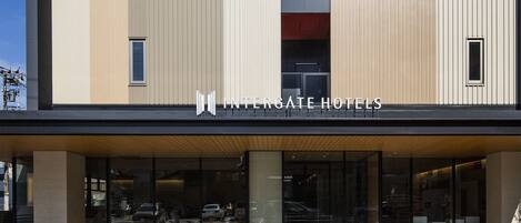 Um hotel moderno com fachada plana, grande entrada de vidro e uma placa de destaque com a inscrição "INTERGATE HOTELS".
