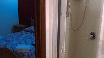 Quarto com cama e área de chuveiro.