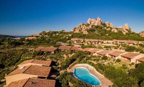 Resort com várias villas, piscina e montanhas ao fundo.