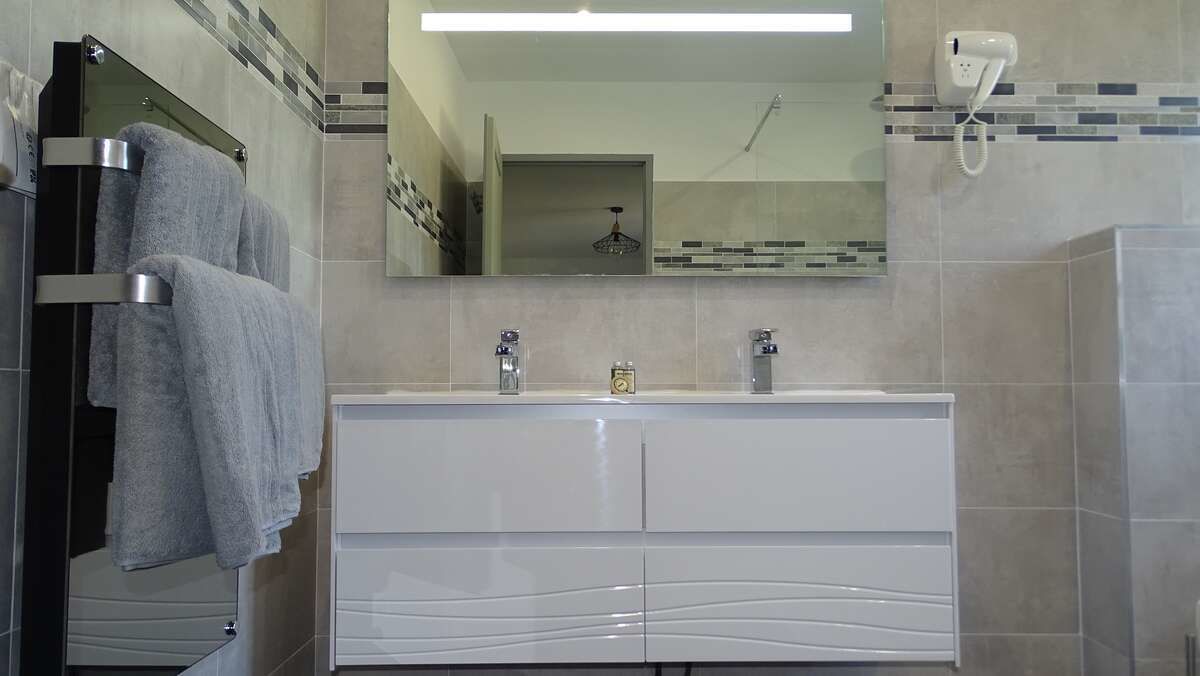 Um banheiro moderno com toucador branco, porta-toalhas, espelho e área de chuveiro.