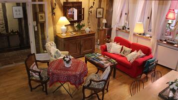Uma sala de estar acolhedora com um sofá vermelho, cadeiras de madeira, uma mesa de centro e uma lareira.