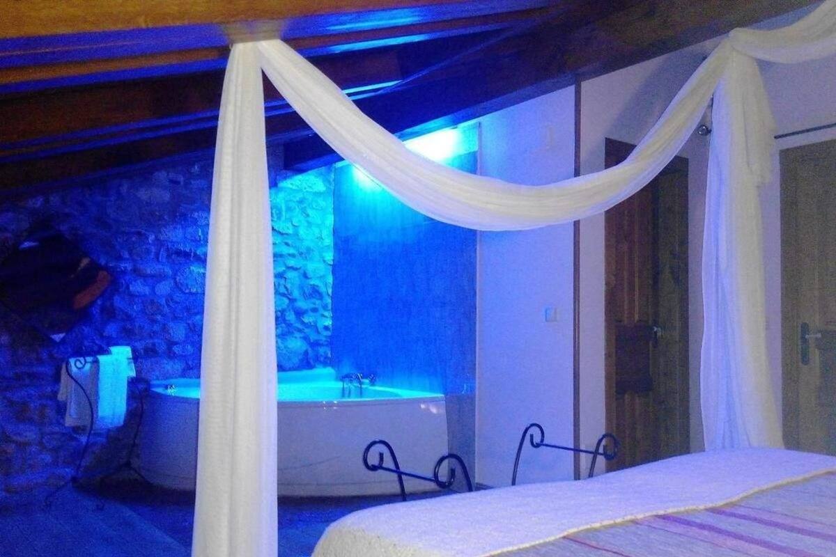 Quarto com cama, banheira e parede de pedra.