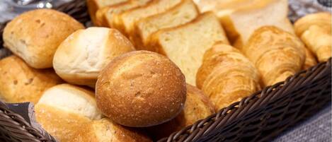 Uma cesta com diversos produtos de panificação, incluindo pães, baguetes e croissants.
