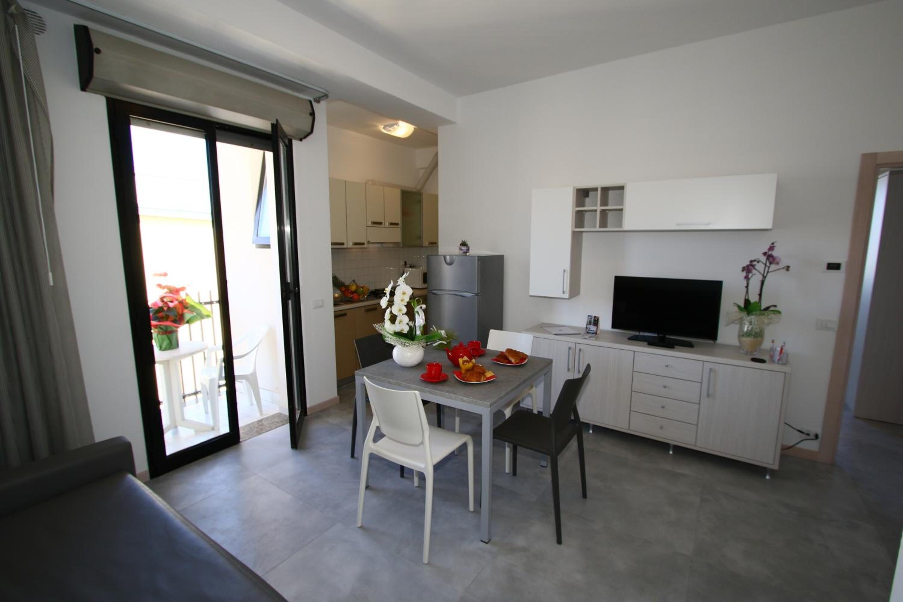 Cozinha compacta com área de refeições, televisão e porta deslizante para área externa.