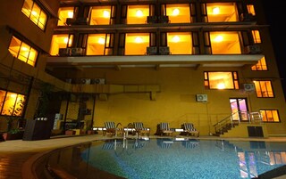 Piscina com espreguiçadeiras e escadaria que leva a um andar superior com janelas iluminadas.