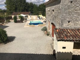 Um pátio com piscina, edifícios de pedra e um caminho de cascalho.