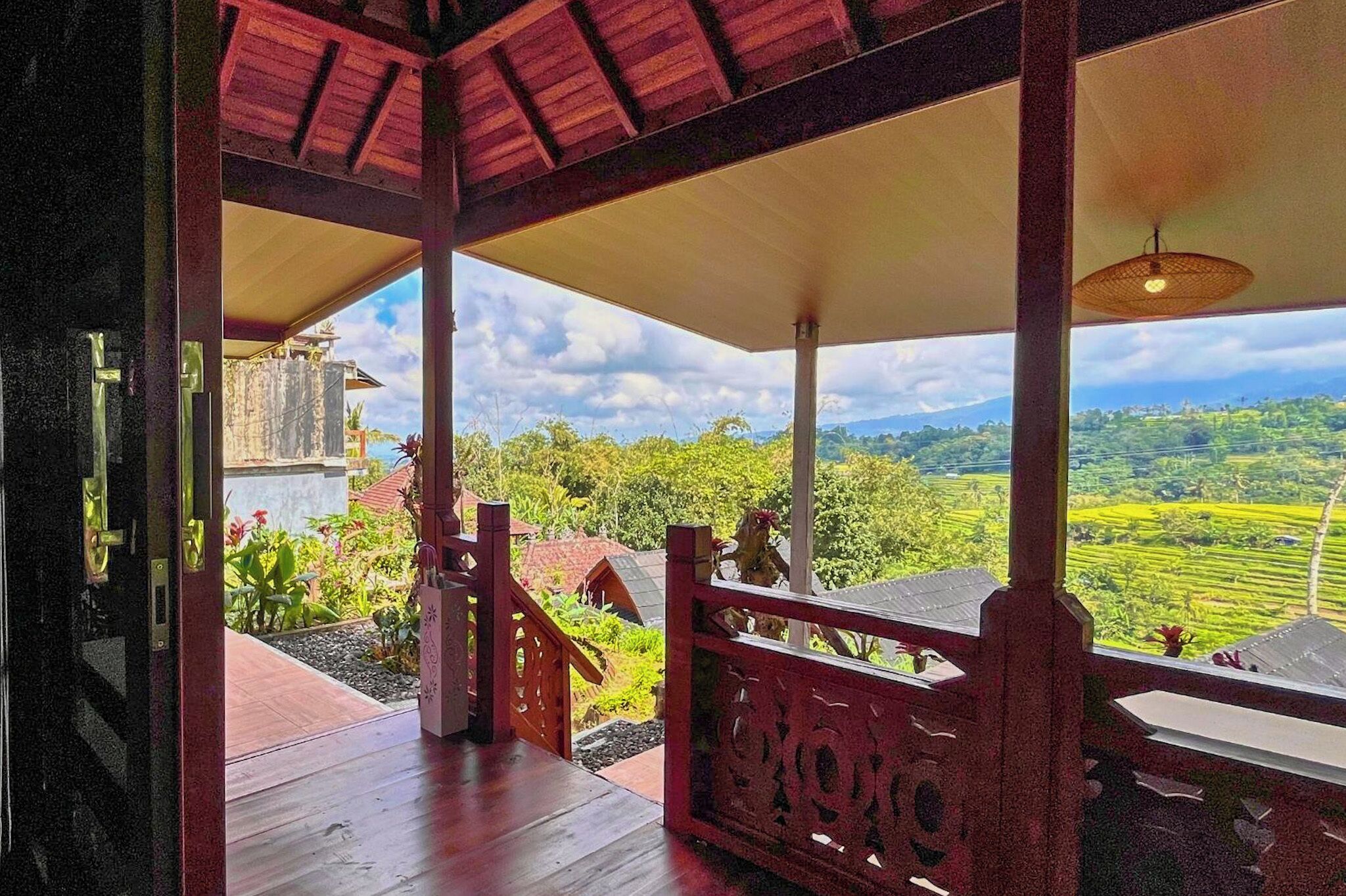 Um deck de madeira com vista para uma paisagem verdejante e colinas ao longe.