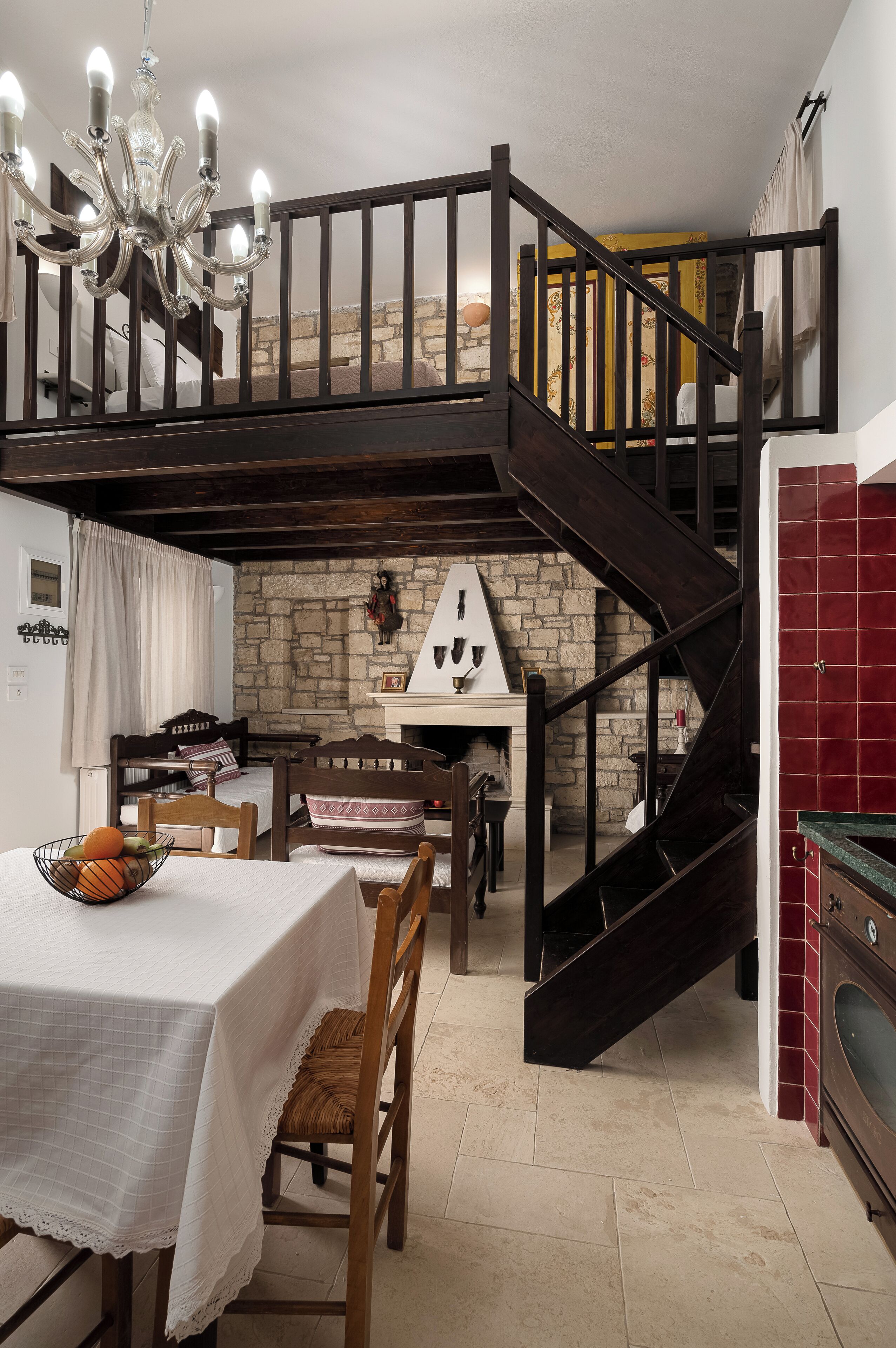 Uma área de refeições com uma mesa posta para dois, um candelabro e uma escada que leva a um andar superior.