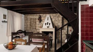 Uma área de refeições com uma mesa posta para dois, um candelabro e uma escada que leva a um andar superior.
