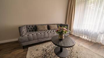 Uma sala de estar com sofá cinza, mesa de centro redonda e tapete estampado.