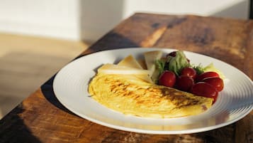 Um prato com omelete, queijo e tomates cereja sobre uma mesa de madeira.