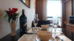 Mesa de restaurante de hotel posta com um vaso de flores, uma garrafa de vinho e diversos copos.