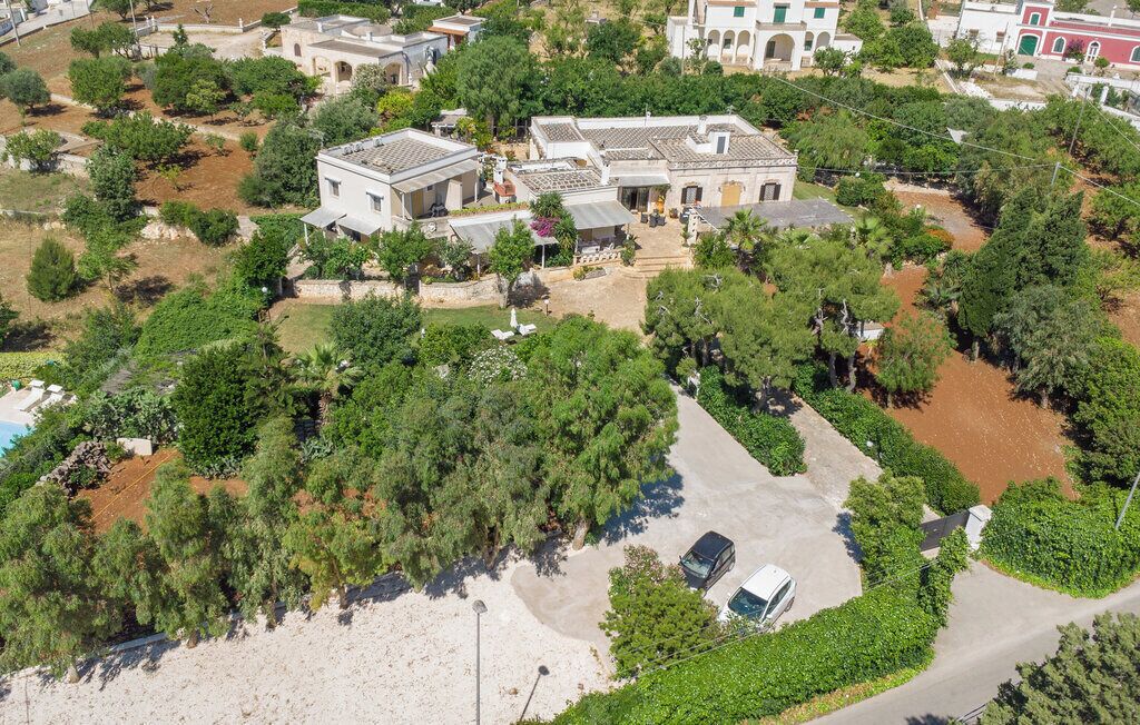 Vista aérea de um bairro residencial com várias casas, área de estacionamento e vegetação ao redor.