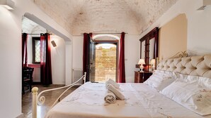 Quarto com cama, mesa de cabeceira, abajur e vista para o exterior.