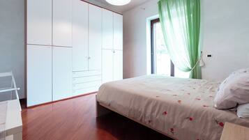 Um quarto com cama, guarda-roupa e janela com cortinas verdes.