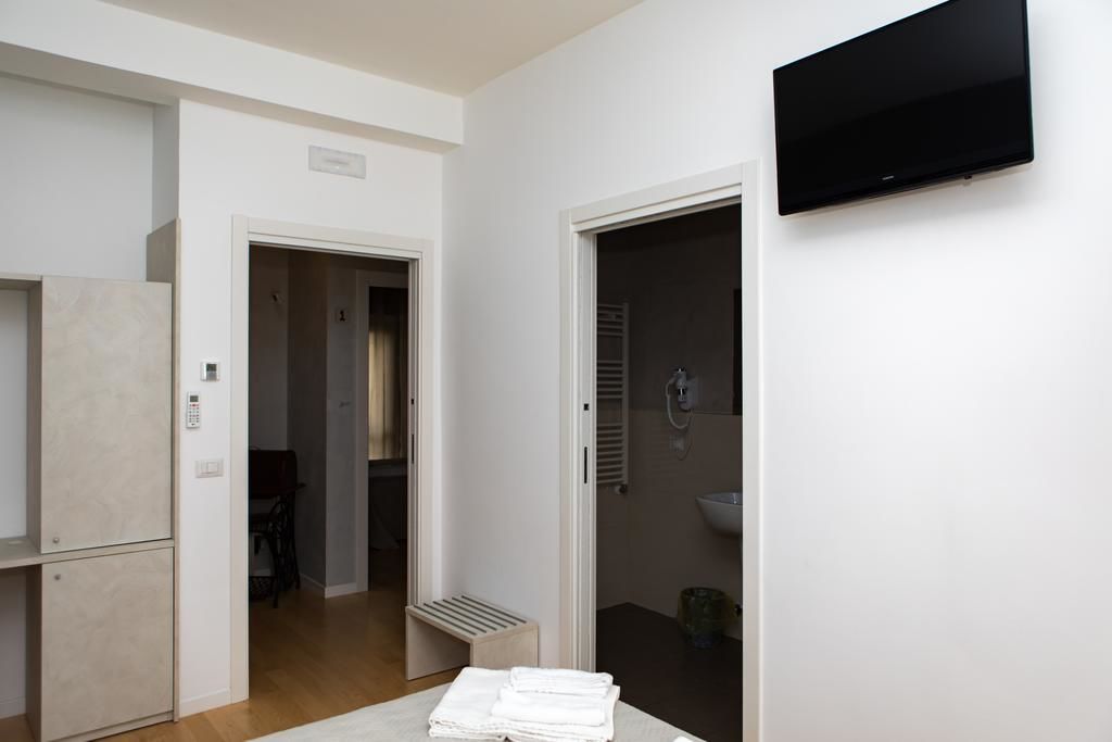 Um apartamento moderno com televisão de tela plana na parede, forno embutido e banheiro visível com pia e porta-toalhas.