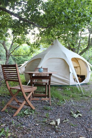 Uma tenda com uma mesa e uma cadeira numa área arborizada.