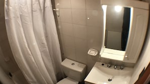 Casa de banho com sanita, lavatório e espelho sobre o lavatório.