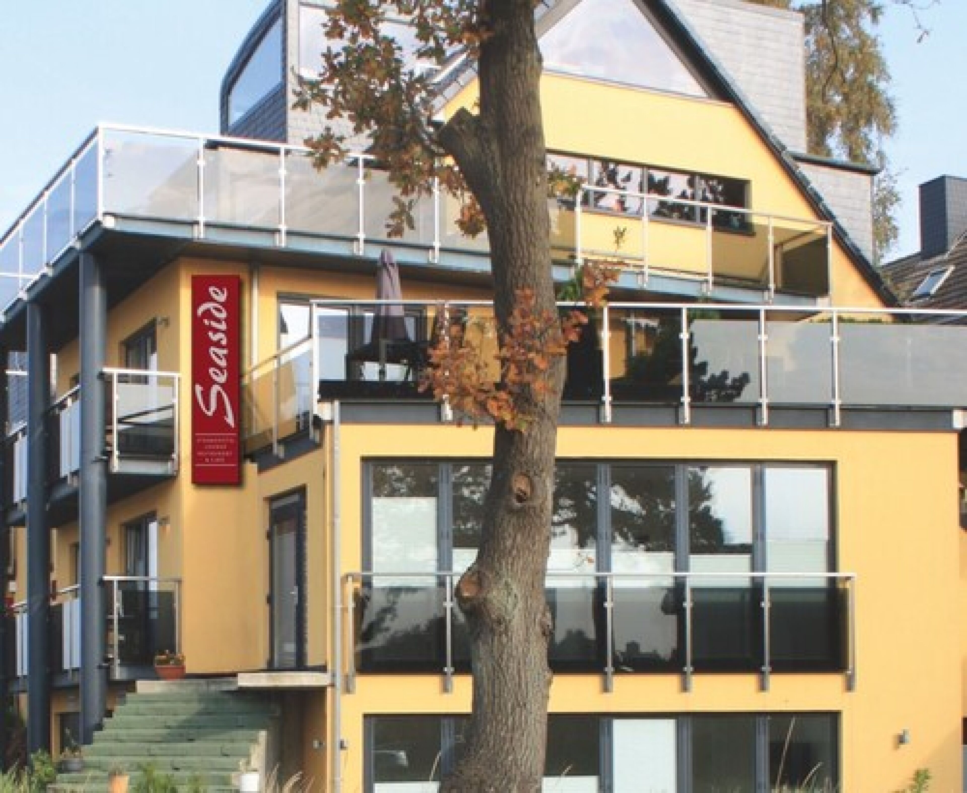 Um edifício moderno com fachada amarela, janelas grandes e uma placa vermelha com a inscrição 'Seaside'.