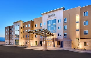 Um hotel de vários andares com entrada coberta, grandes janelas e uma placa com a inscrição 'Staybridge Suites'.