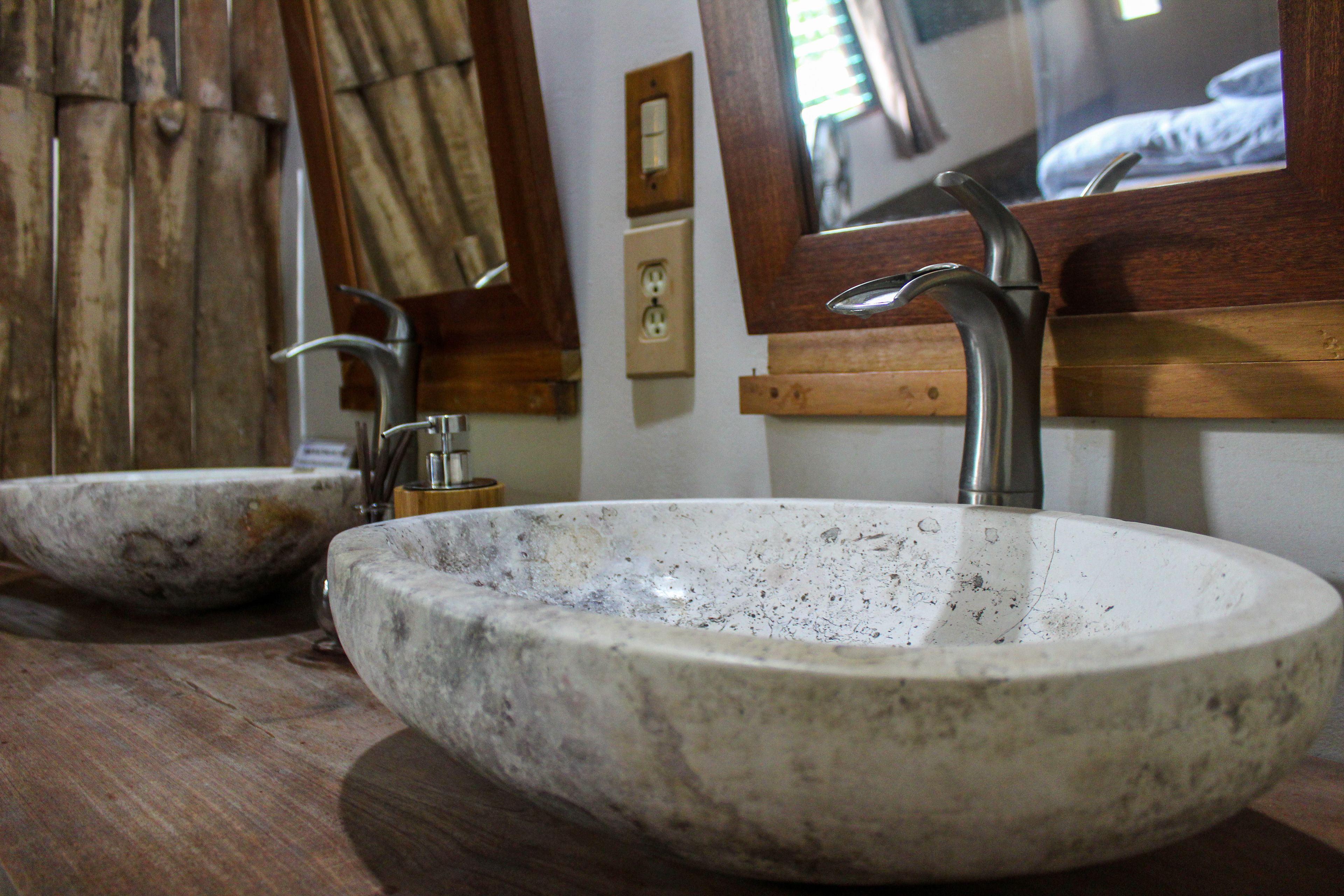 Casa de banho com duas pias grandes e redondas de mármore branco com torneiras.