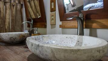 Casa de banho com duas pias grandes e redondas de mármore branco com torneiras.