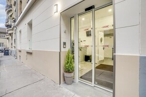 Um edifício moderno com entrada de vidro, um vaso de planta e interior visível com uma área de recepção.