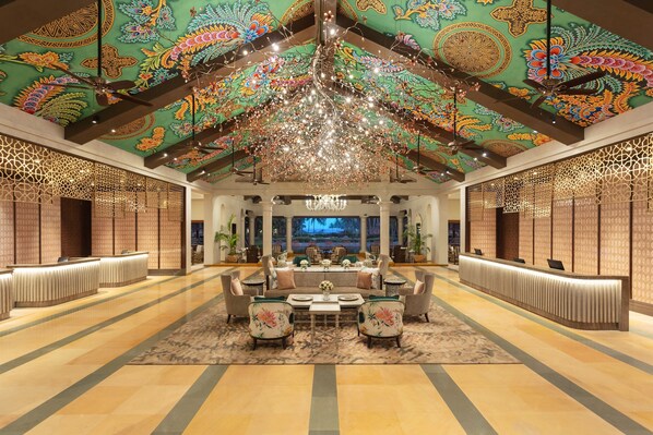 Um hall amplo com teto alto, detalhe ornamentado no teto e um lustre.