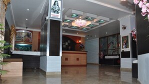 Um saguão de hotel com balcão de recepção, um candelabro e um grande aquário.