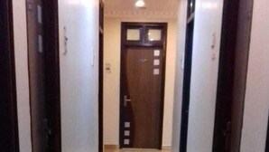 Um corredor com chão de azulejos que leva a uma porta com janela.