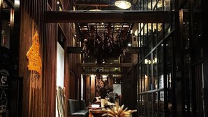 Um interior em madeira com área de estar central, uma estrutura suspensa decorativa e uma escadaria para um andar superior.