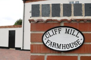 Paredes de tijolo com uma placa que diz "CLIFF MILL FARMHOUSE".