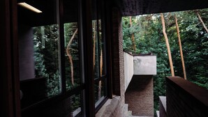 Interior moderno com amplas janelas com vista para uma área arborizada.