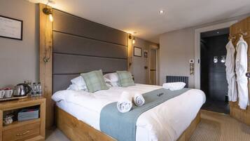 Quarto de hotel com uma cama grande, cabeceira de madeira, mesas de cabeceira e um guarda-roupa.